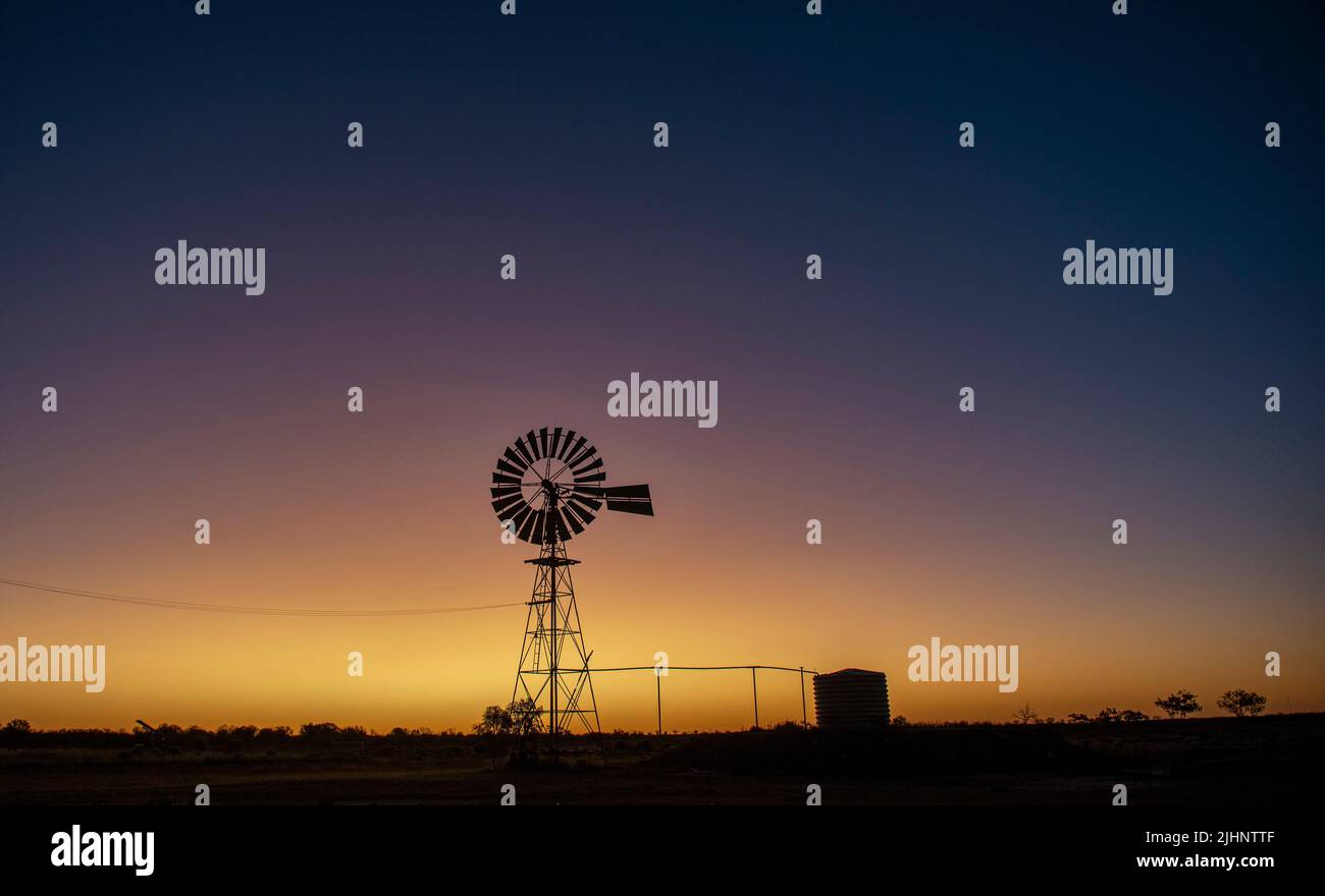 Sunset in outback Queensland with a water tank and windmill Stock Photo ...