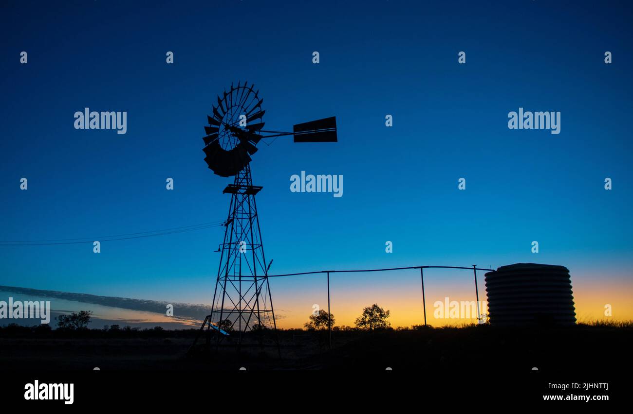 Sunset in outback Queensland with a water tank and windmill Stock Photo ...