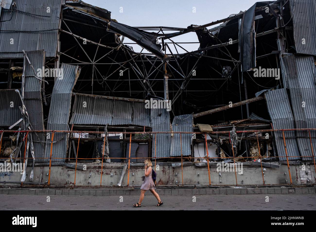 A woman seen walking past a destroyed shopping mall in Kharkiv. (Photo ...