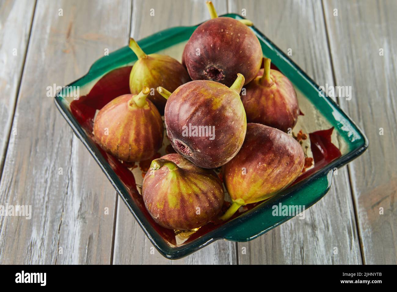 Fresh figs In green plate on wooden background Stock Photo - Alamy