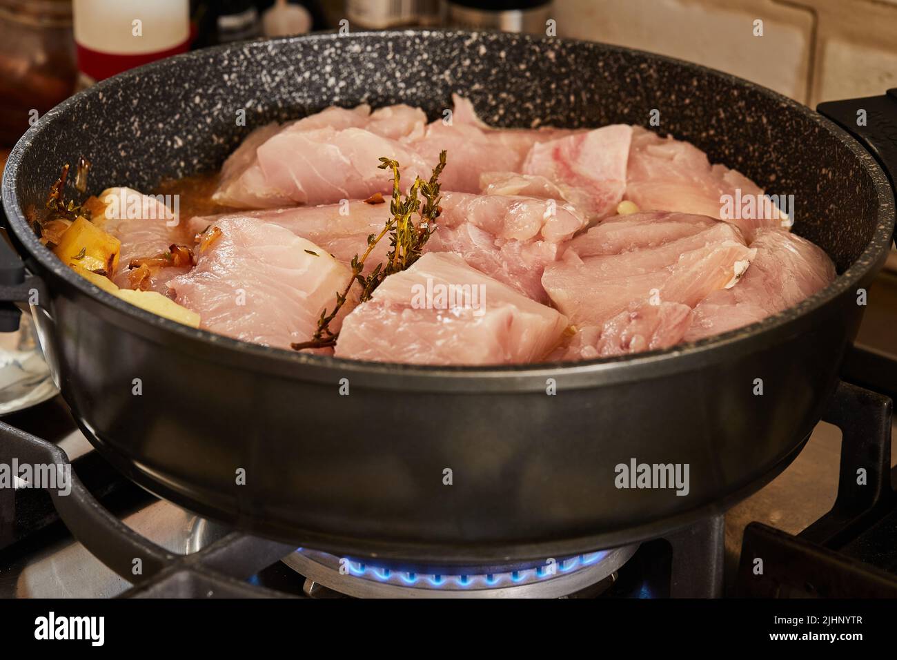 Fish stewed with carrots, mushrooms and potatoes is fried in pan on gas ...