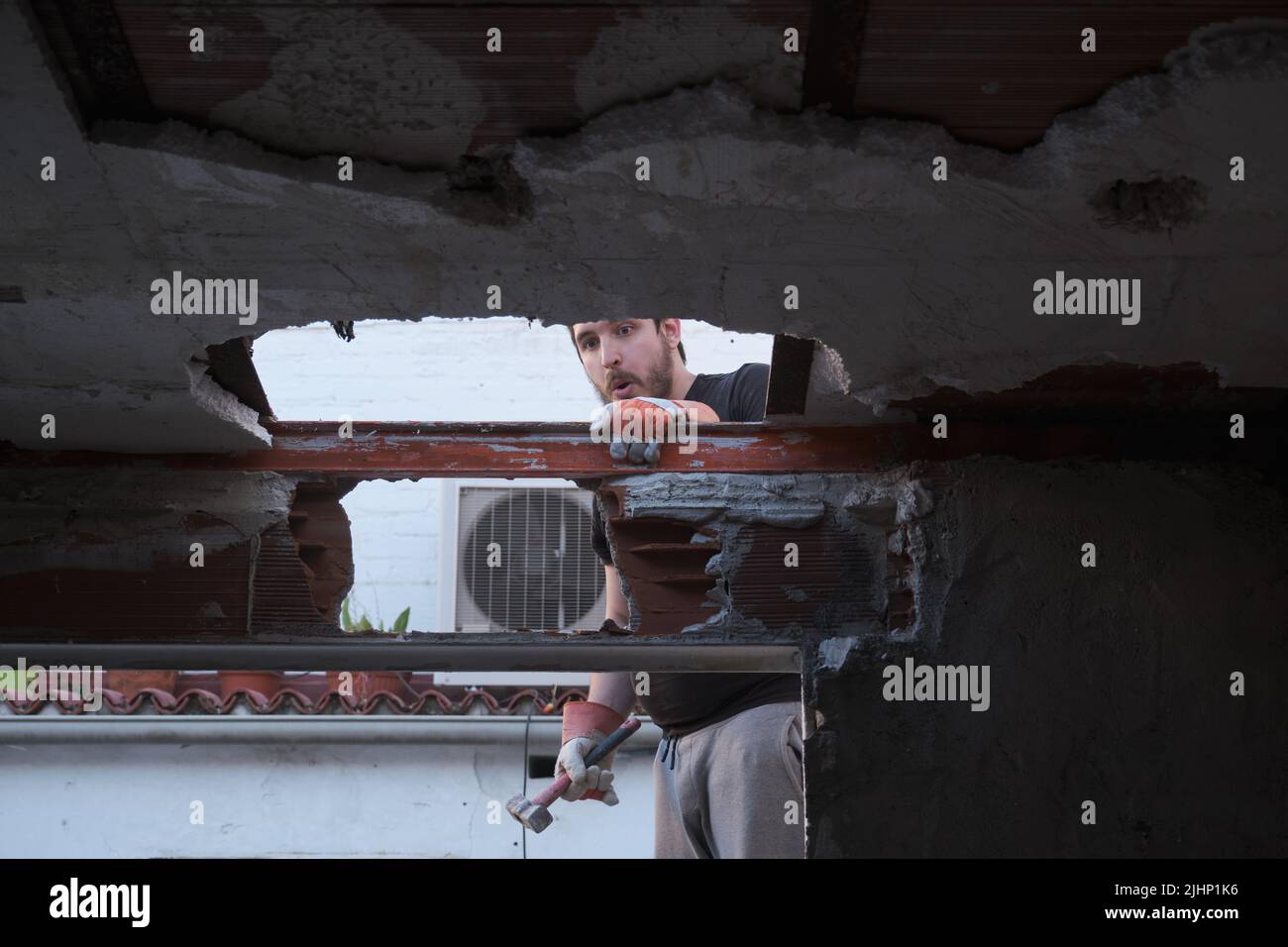 Young man tearing the ceiling down and realizing that he broke ...
