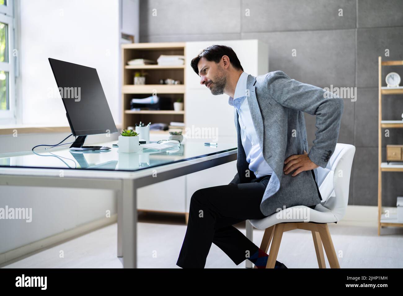 Bad Posture Sitting In Office With Backache In Chair Stock Photo - Alamy