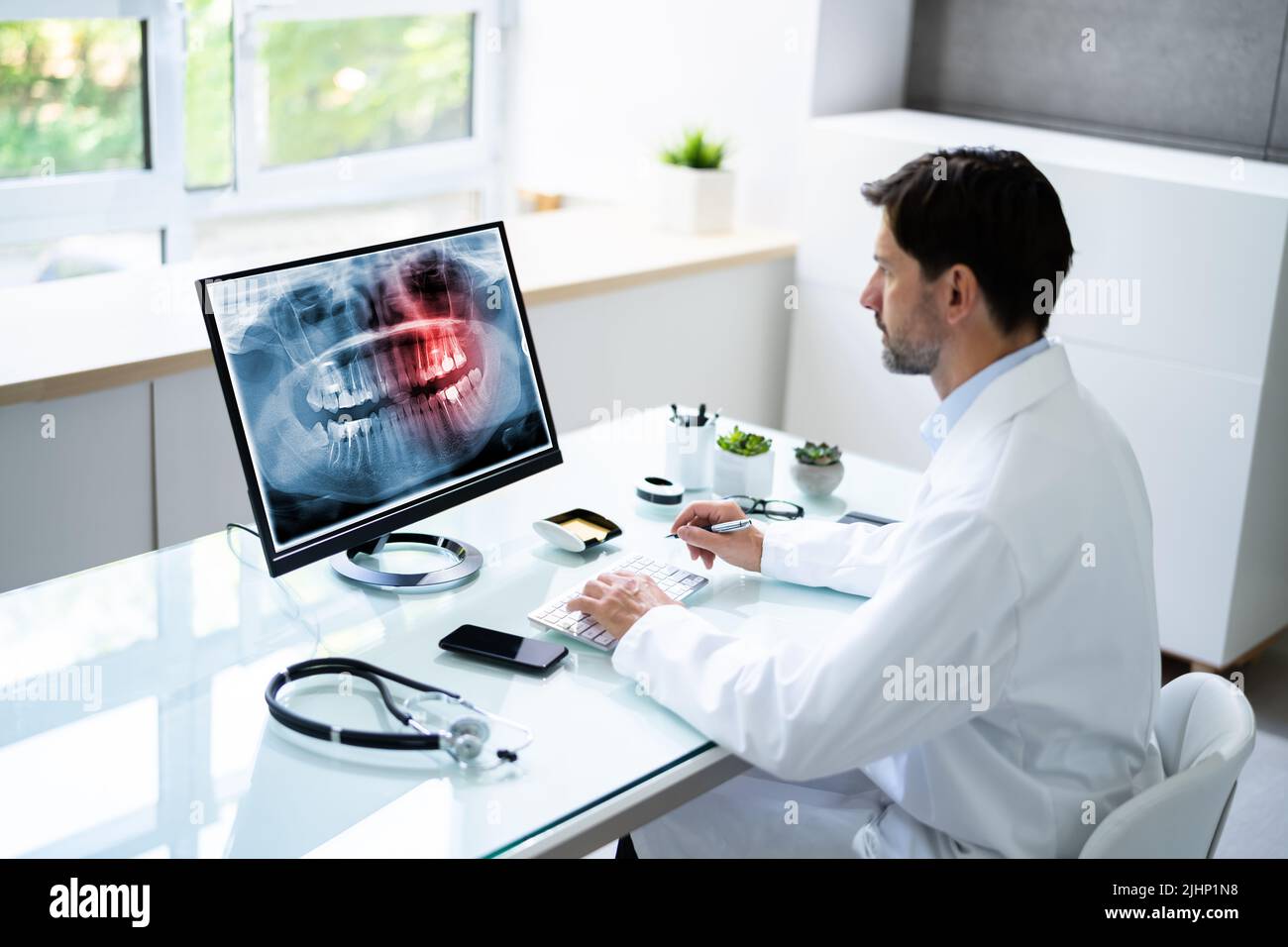 Mature Male Dentist Looking At Teeth X-ray On Computer In Clinic Stock ...