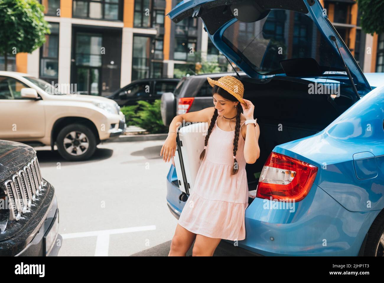 Woman packing her suitcase into luggage boot of the car Stock Photo - Alamy
