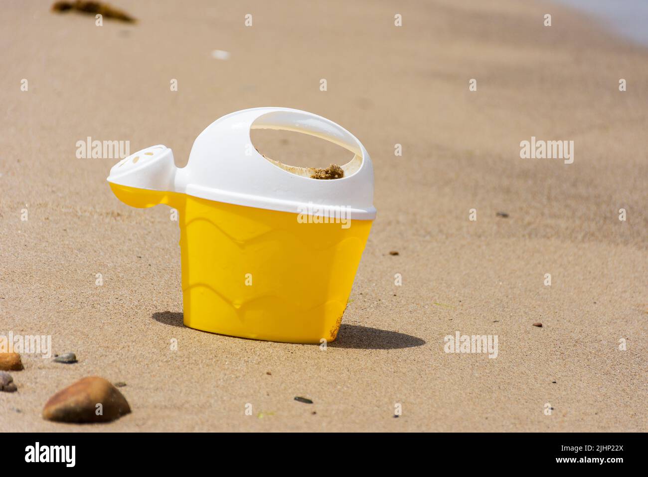 Close up a yellow kid's plastic toy bucket on the beach Stock Photo - Alamy