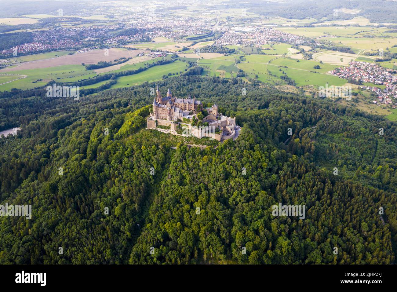 Drone shot of Hohenzollern Castle on forested mountain top in the ...