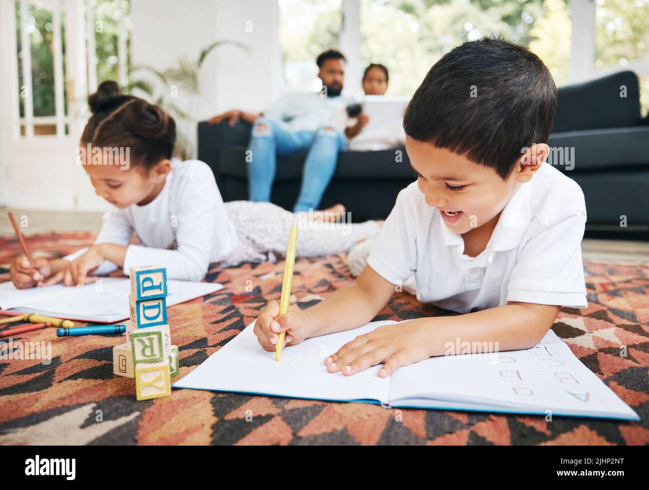 Little boy and girl drawing with colouring pencils lying on living room ...