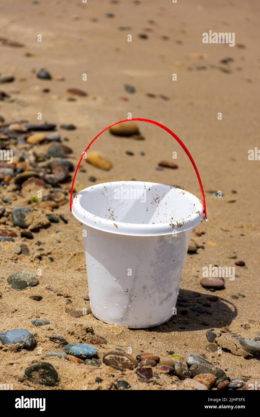 Close up a white kid's plastic toy bucket on the beach Stock Photo - Alamy