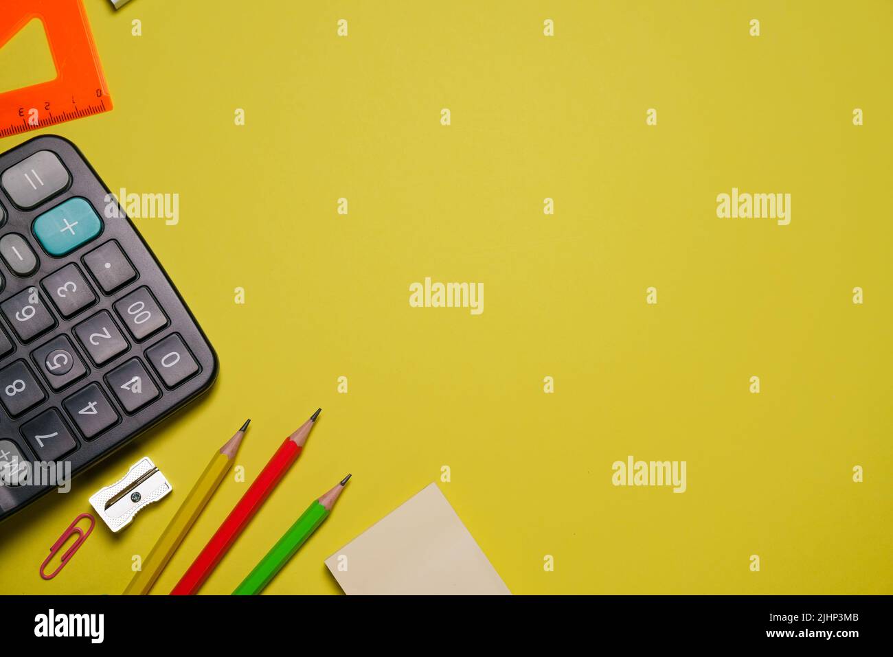 Calculator and stationery in different colors on a yellow background ...