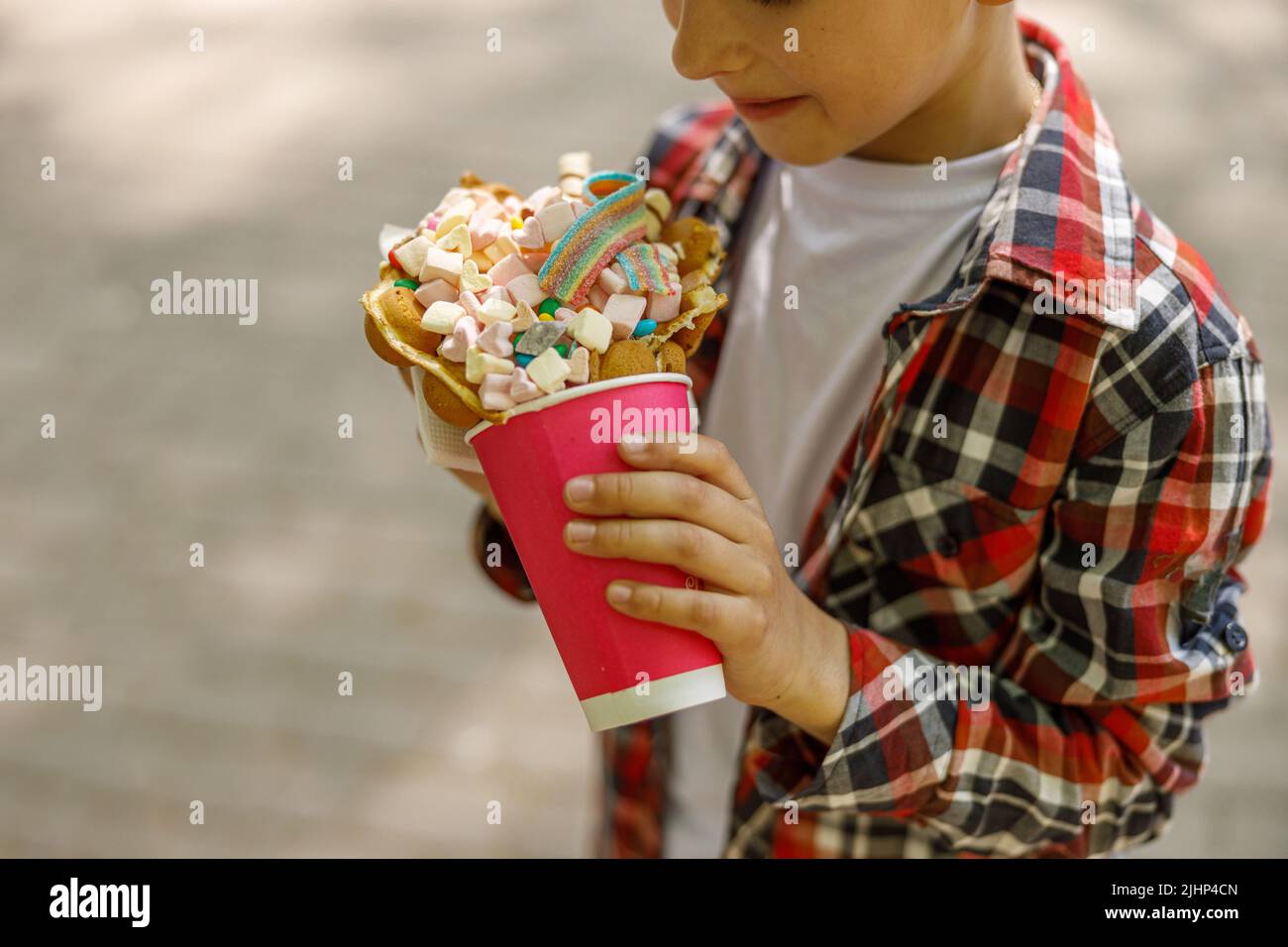 Close up of sweet waffle with marshmallow in hands of small cute boy ...