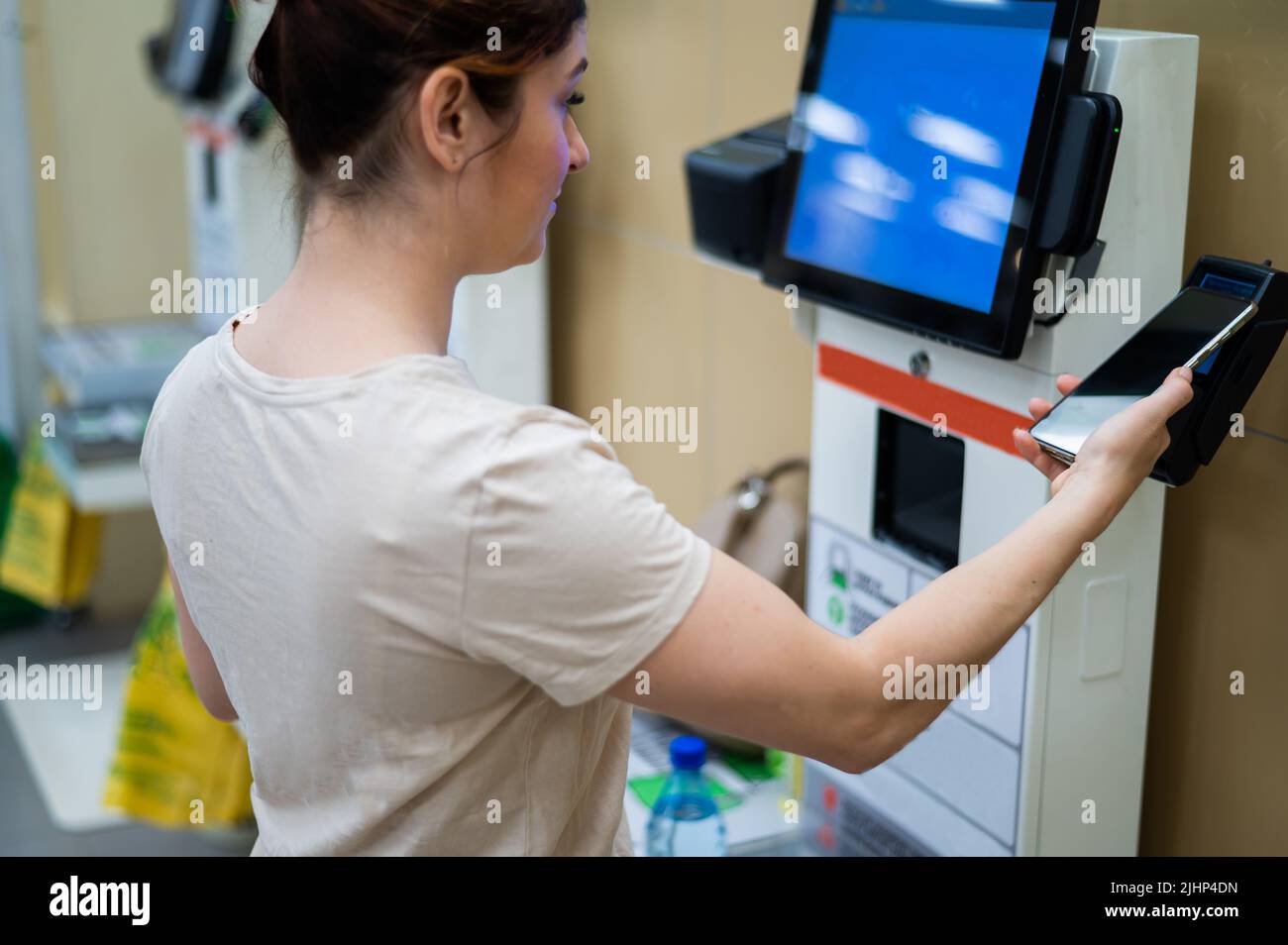 Woman paying with smartphone in store at self-checkout counter Stock ...