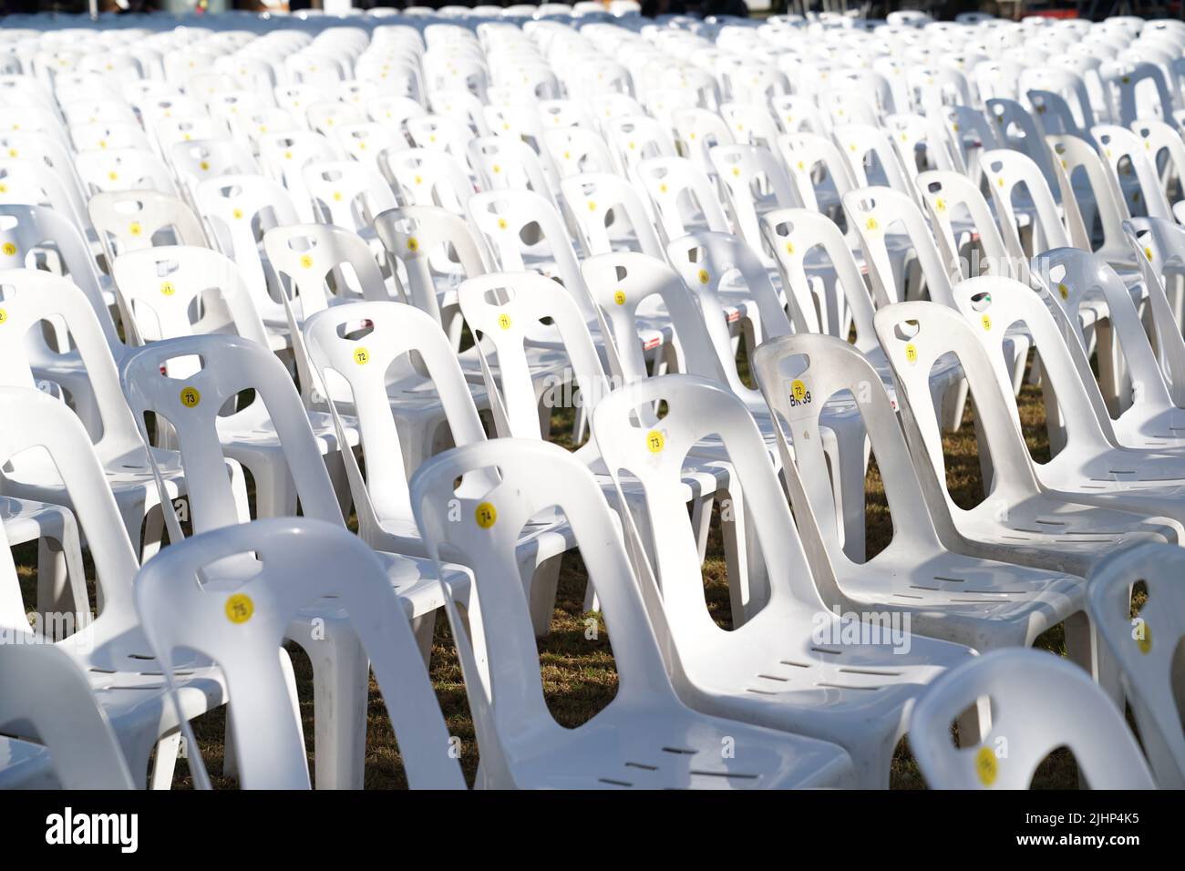Many white plastic chairs were set up in a square area with the row and ...