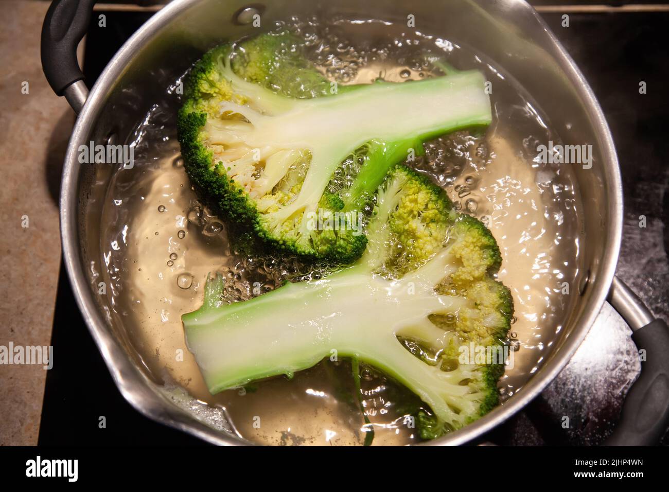 Broccoli inflorescences cut lengthwise are cooked in boiling water in a ...