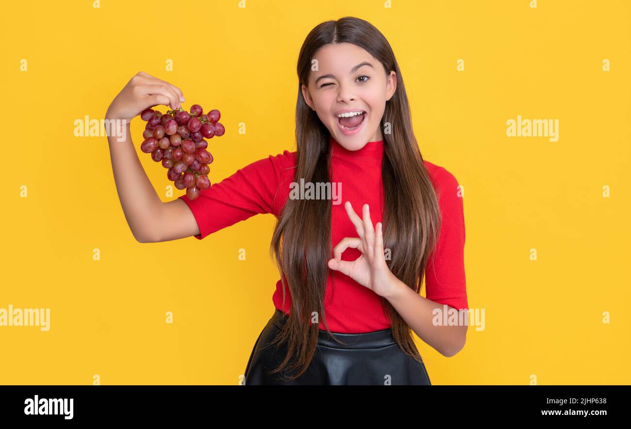 winking teen kid hold bunch of grapes on yellow background Stock Photo ...