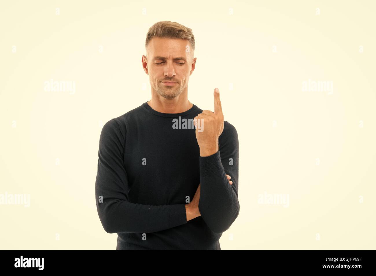 Serious man in black sweatshirt look at raised finger pointing up ...