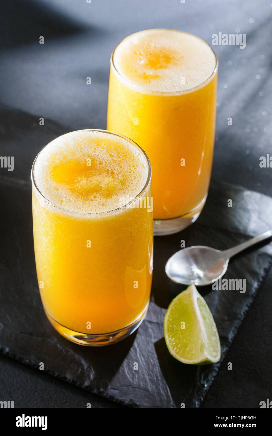 Fresh summer fruit drink on a black background. Orange color drink made ...