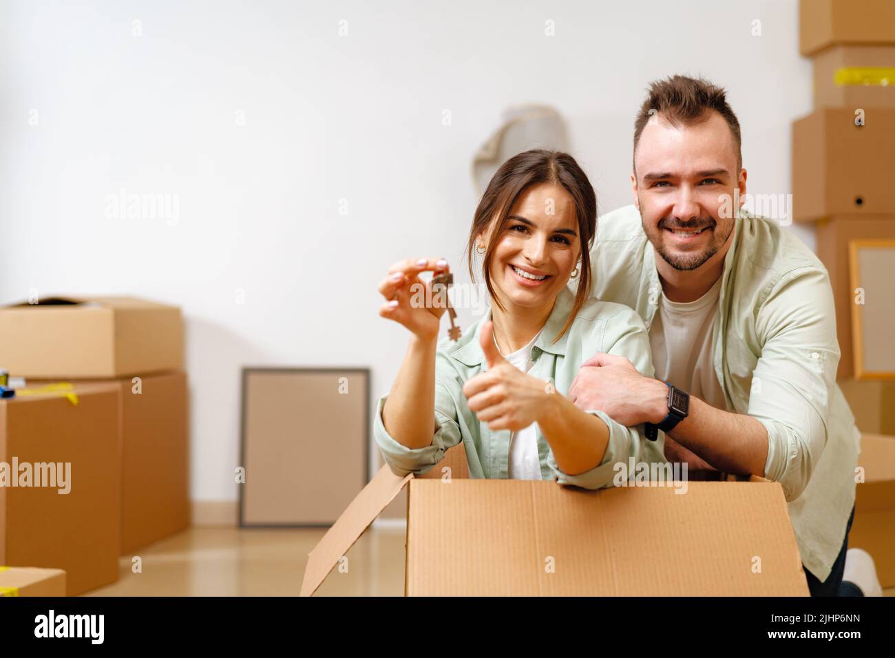 Young happy couple in room with moving boxes at new home Stock Photo ...