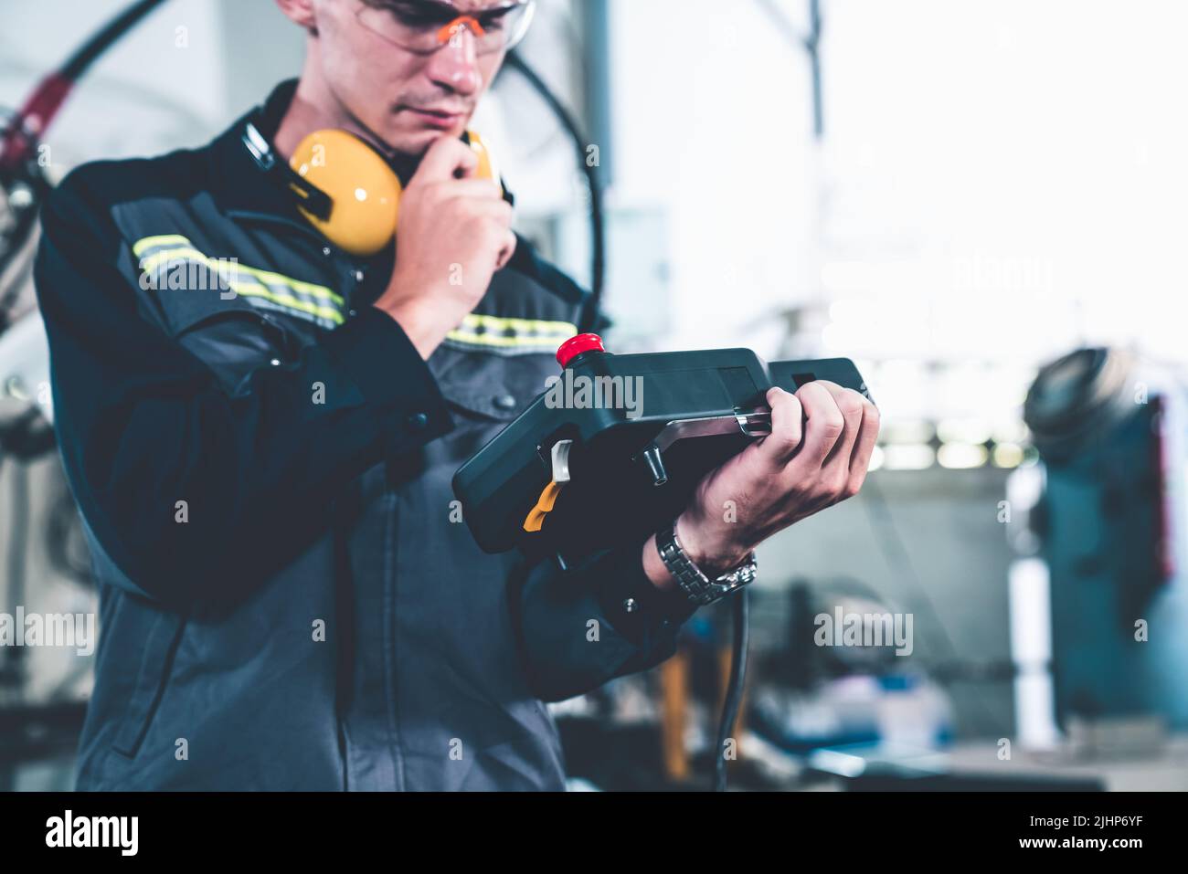 Young factory worker working with adept robotic arm in a workshop . Industry robot programming ...