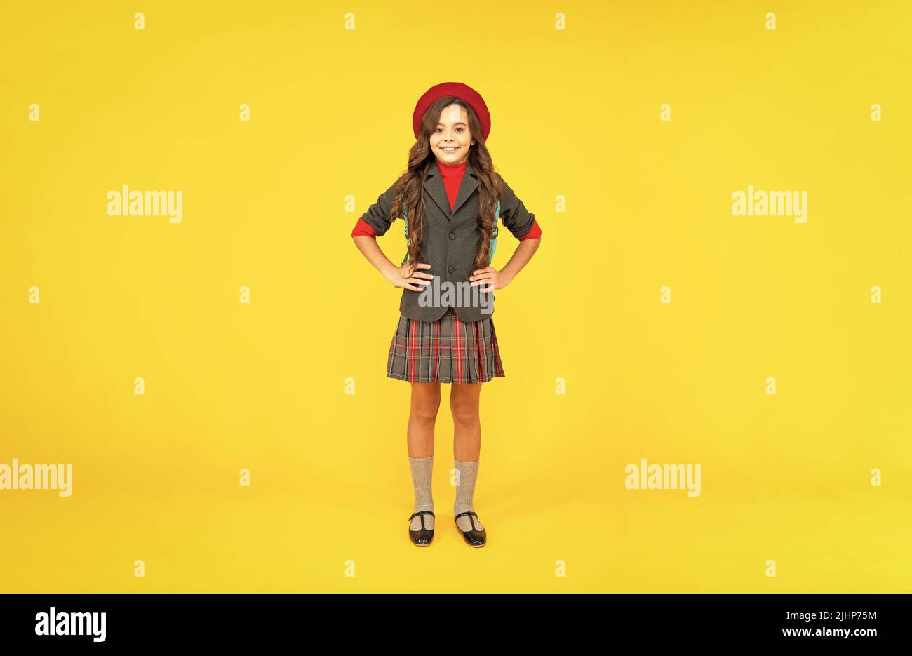 positive child in school uniform and beret full length on yellow ...