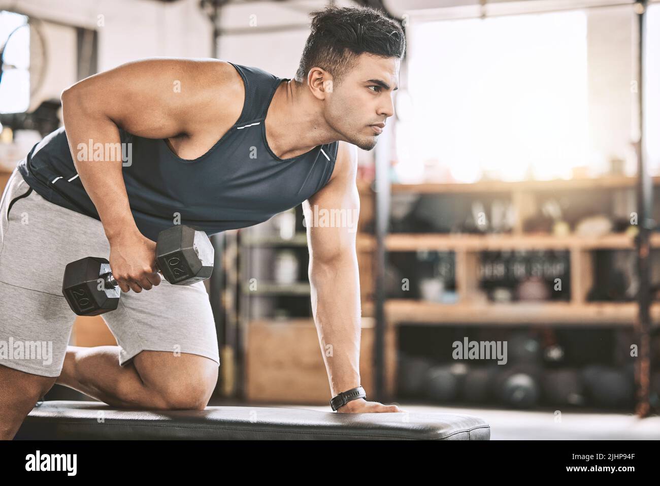 Serious bodybuilder lifting weights. Young athlete building strong ...