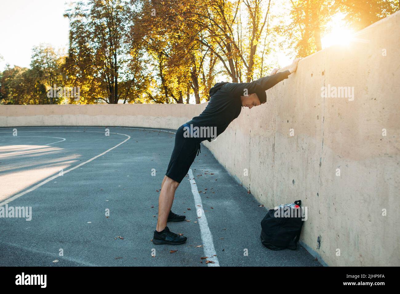 Concentrated young sportsman stretching hi-res stock photography and ...