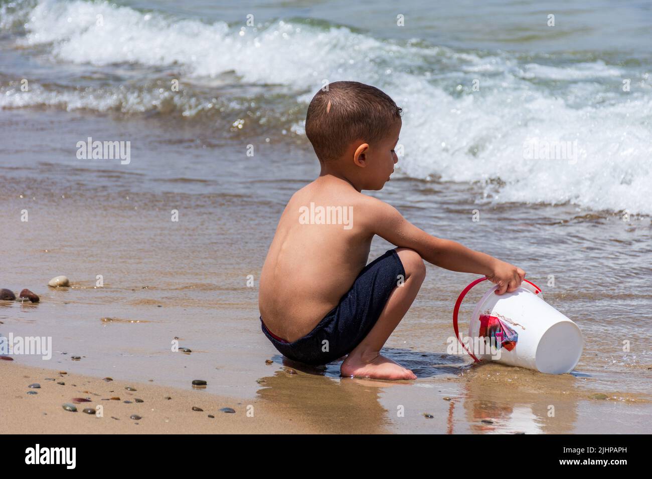 Back view of a young boy playing on the beach. Summer vacation concept ...