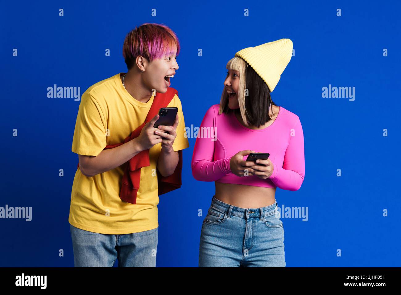 Asian teenagers with multicolored hair screaming while using cellphones ...