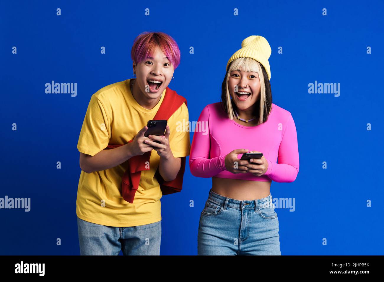 Asian teenagers with multicolored hair screaming while using cellphones ...