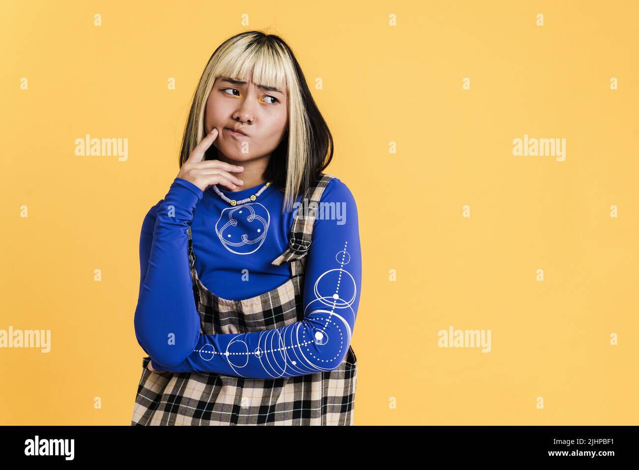 Asian girl with piercing frowning while looking aside isolated over ...