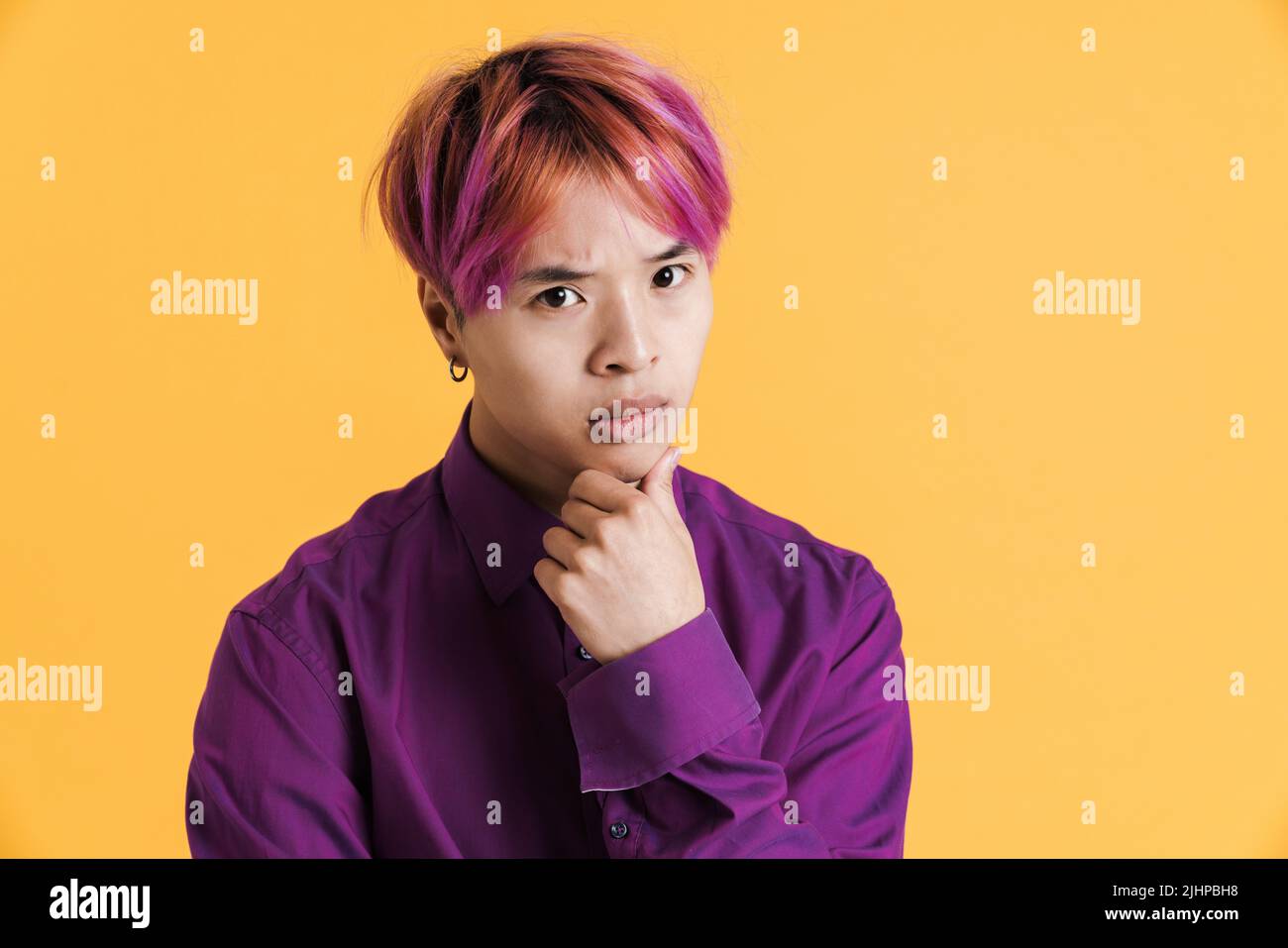 Asian boy with pink hair frowning and looking at camera isolated over ...