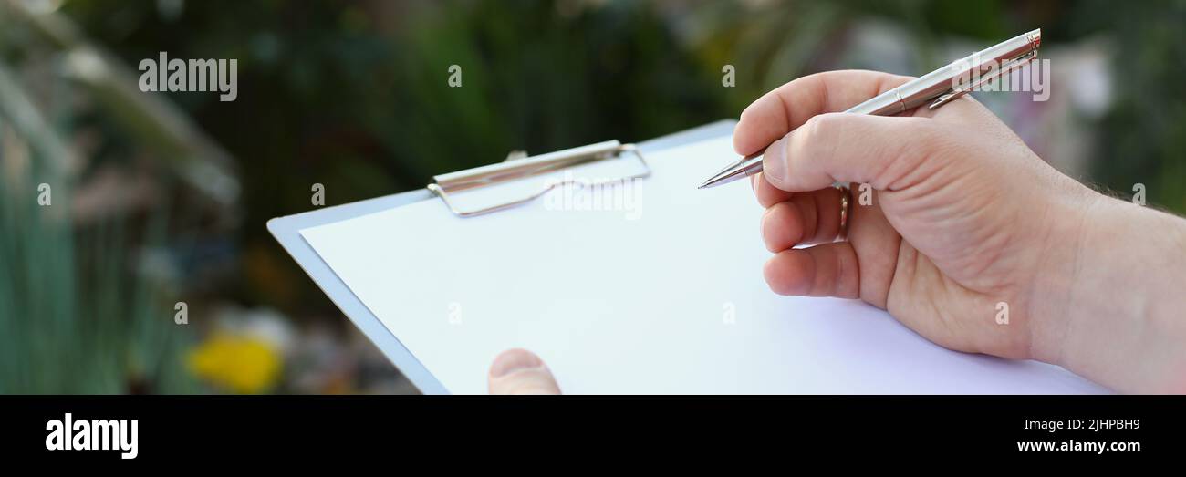 Human hand writing on clipboard with white paper, pen and blank ...