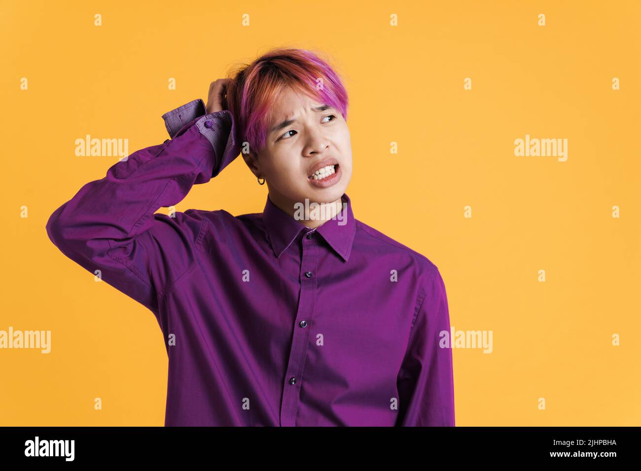 Asian boy with pink hair frowning and looking aside isolated over ...