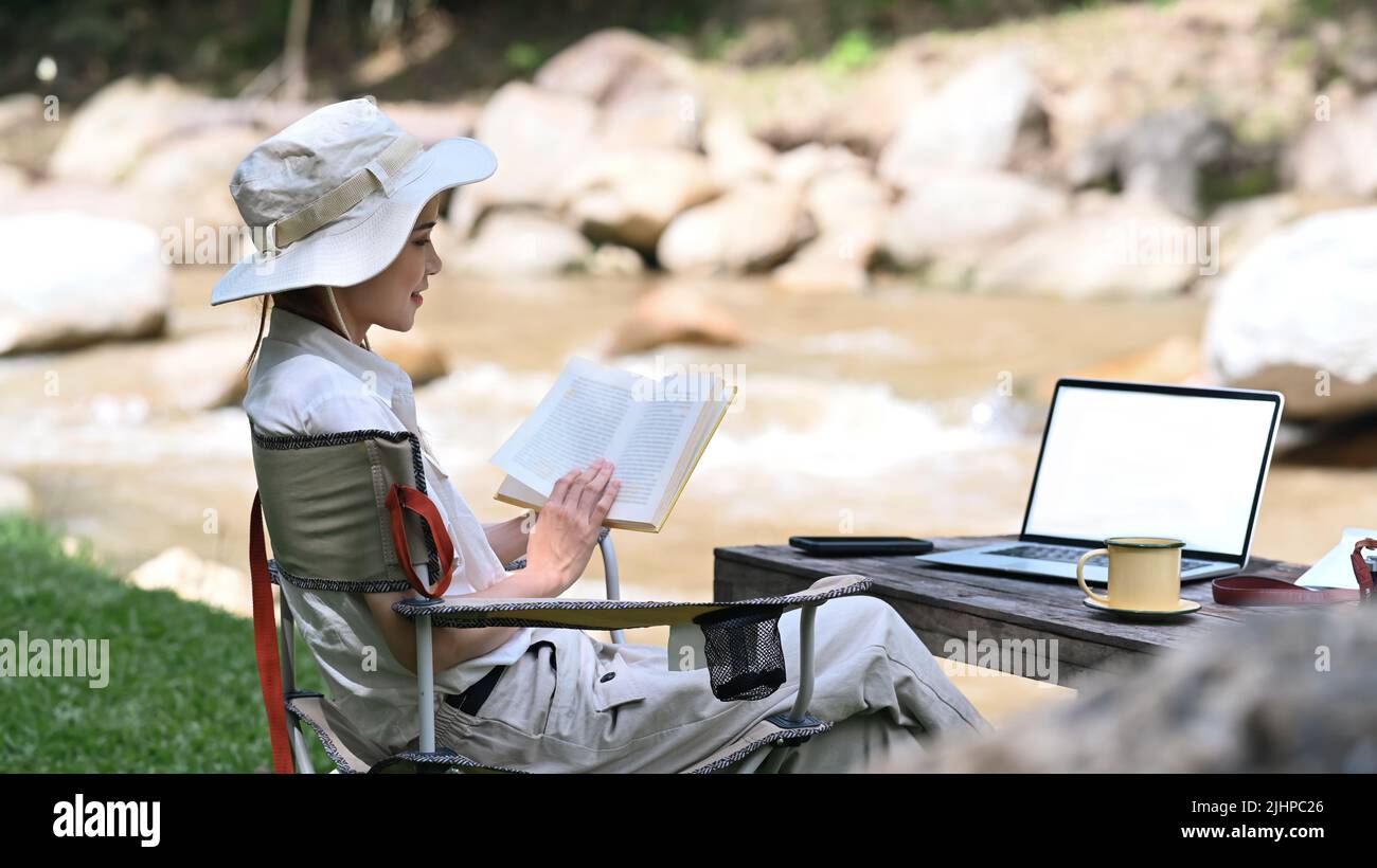 Calm female traveler reading book, enjoying camping alone near the ...