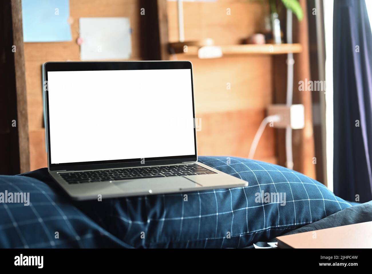 Laptop on the bed in morning time with soft light from window. Empty ...
