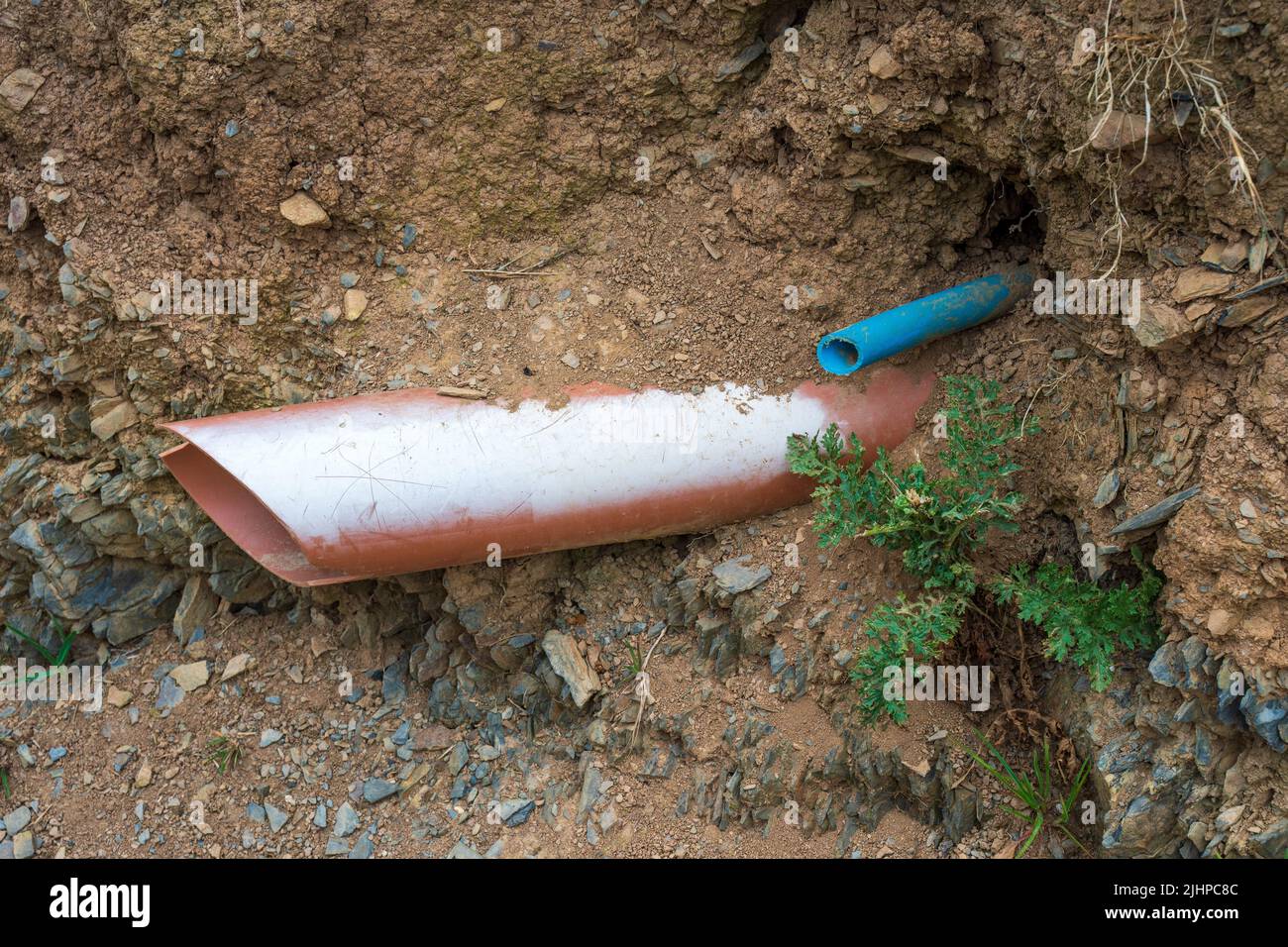 earth excavation to expose plastic drainage pipe and alkathene water ...