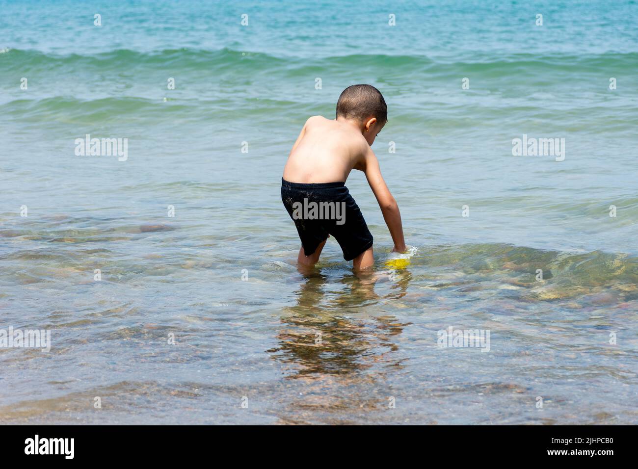 Back view of a young boy playing on the beach. Summer vacation concept ...