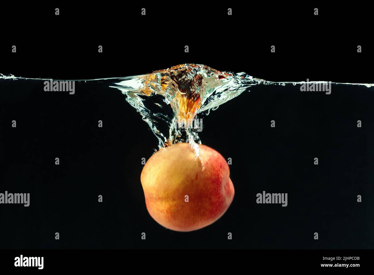 Peach dropped into water with bubbles Stock Photo - Alamy