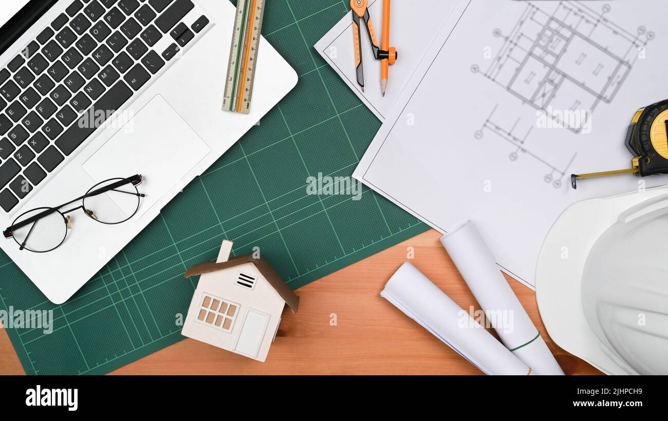 Engineer office desk with laptop, blueprints, hard hat and engineering ...