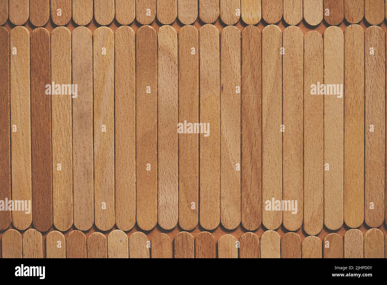 Wooden popsicle sticks, placed in a rows on top of a beige background ...