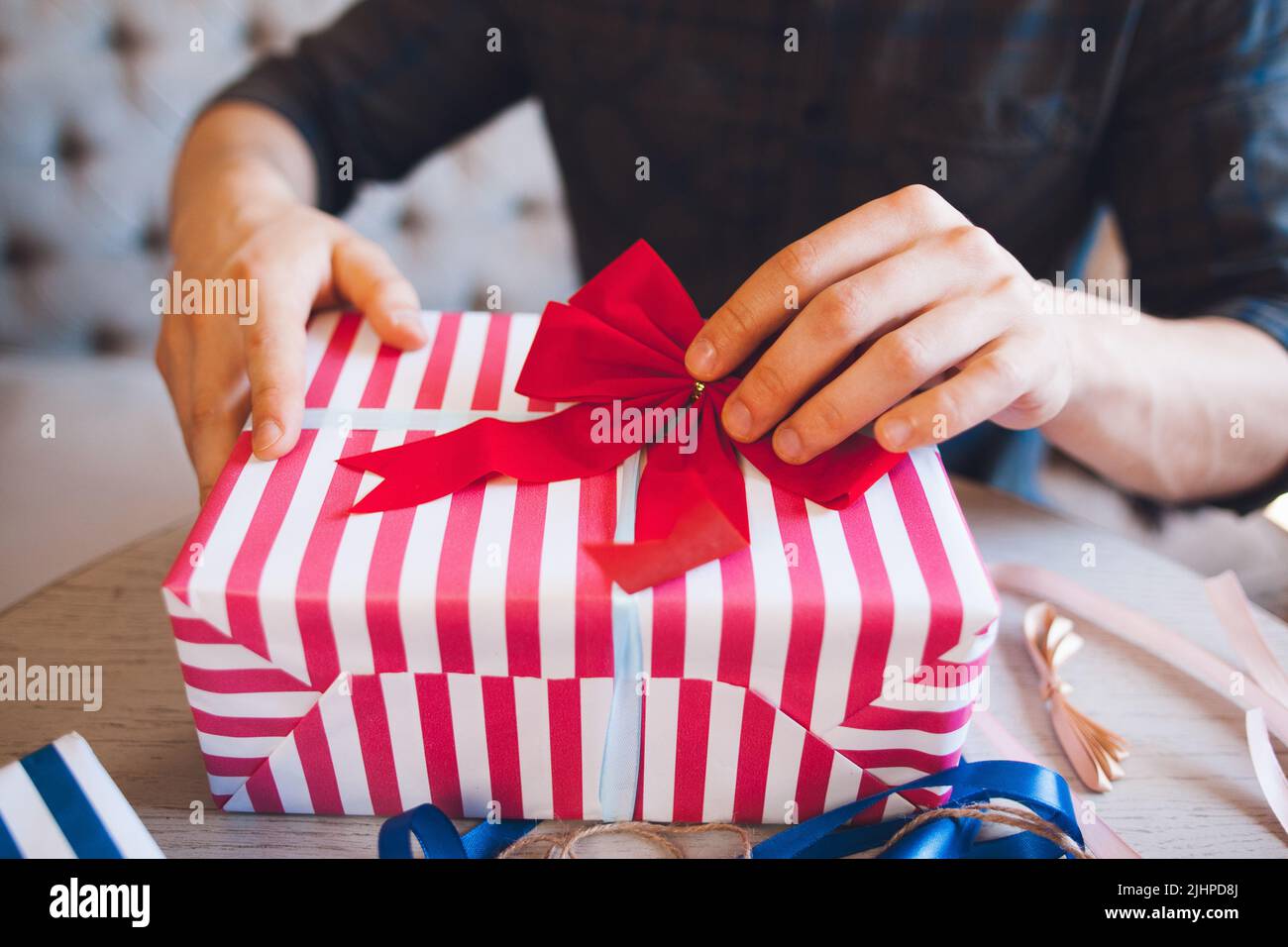 Man decorating gift box with red bow Stock Photo - Alamy