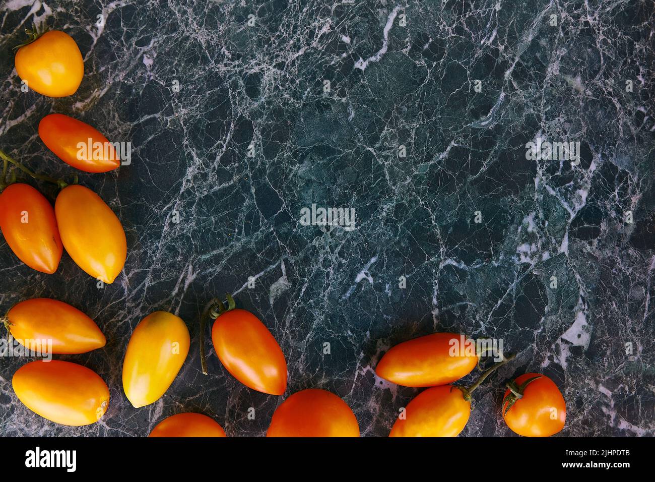 Harvesting bright orange and yellow tomatoes on green marble background ...