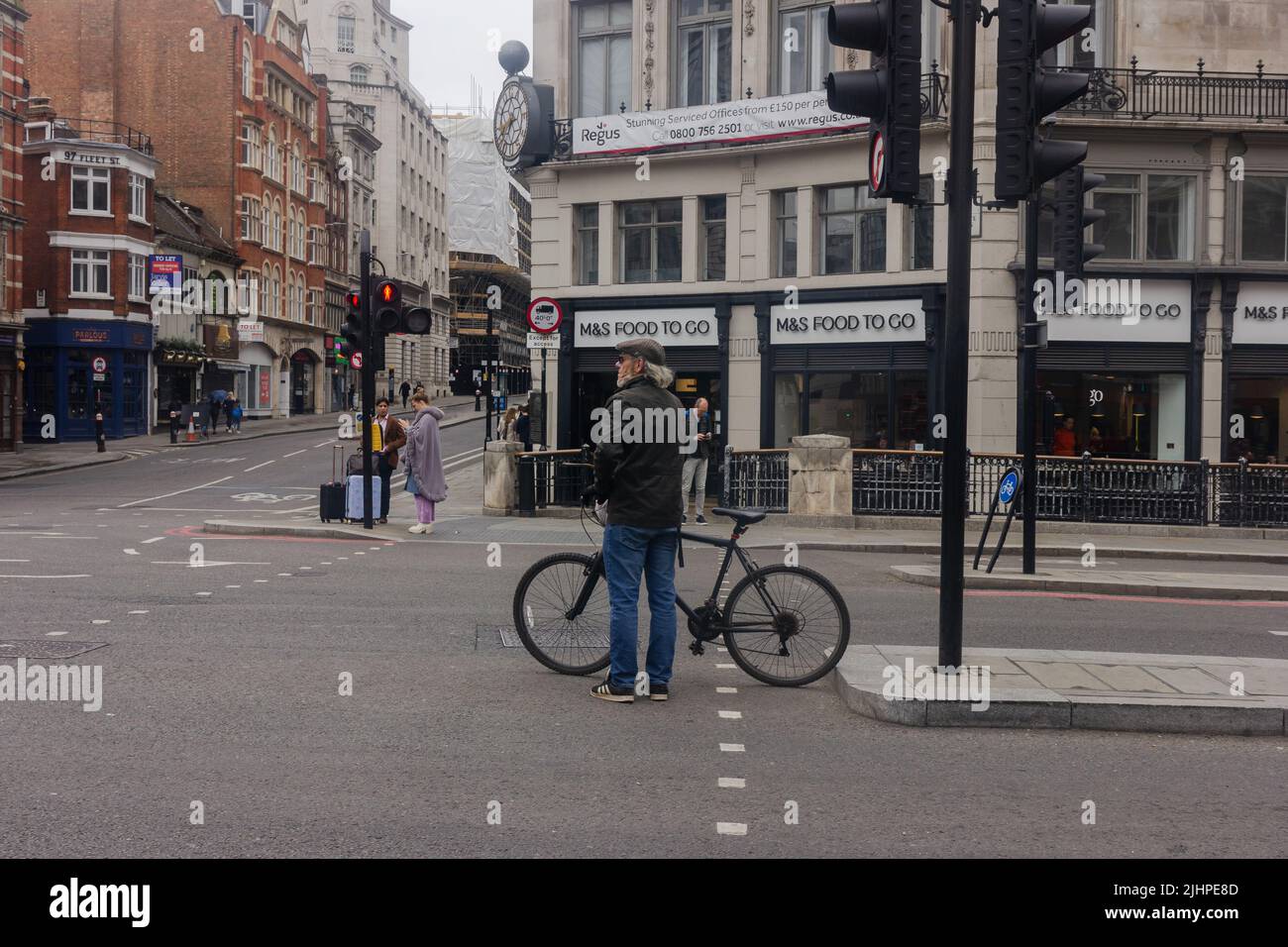 London, UK- May 2022: London street view, a man holding his bicycle at ...