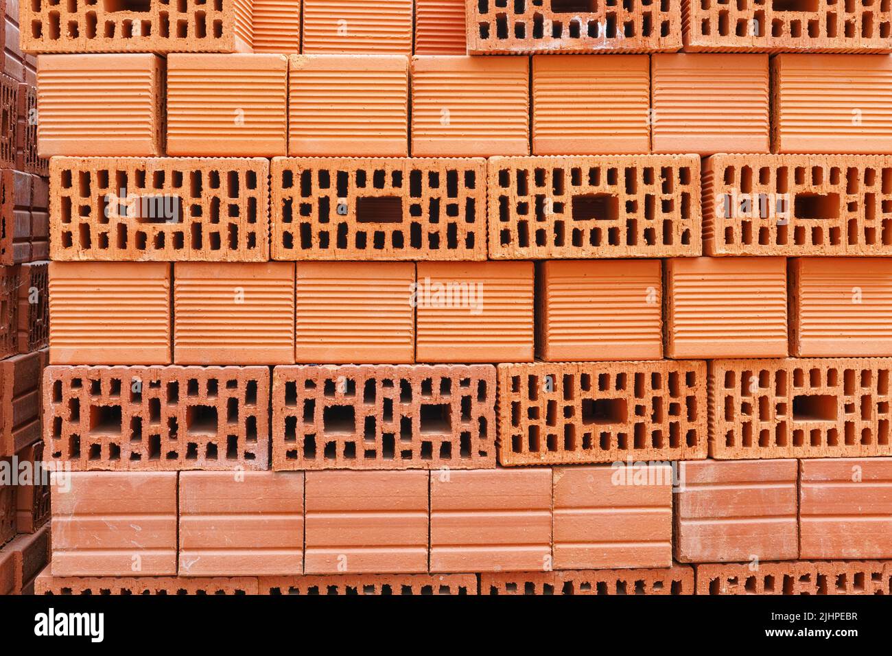 Stacked red bricks at a construction site close up. Industrial and ...