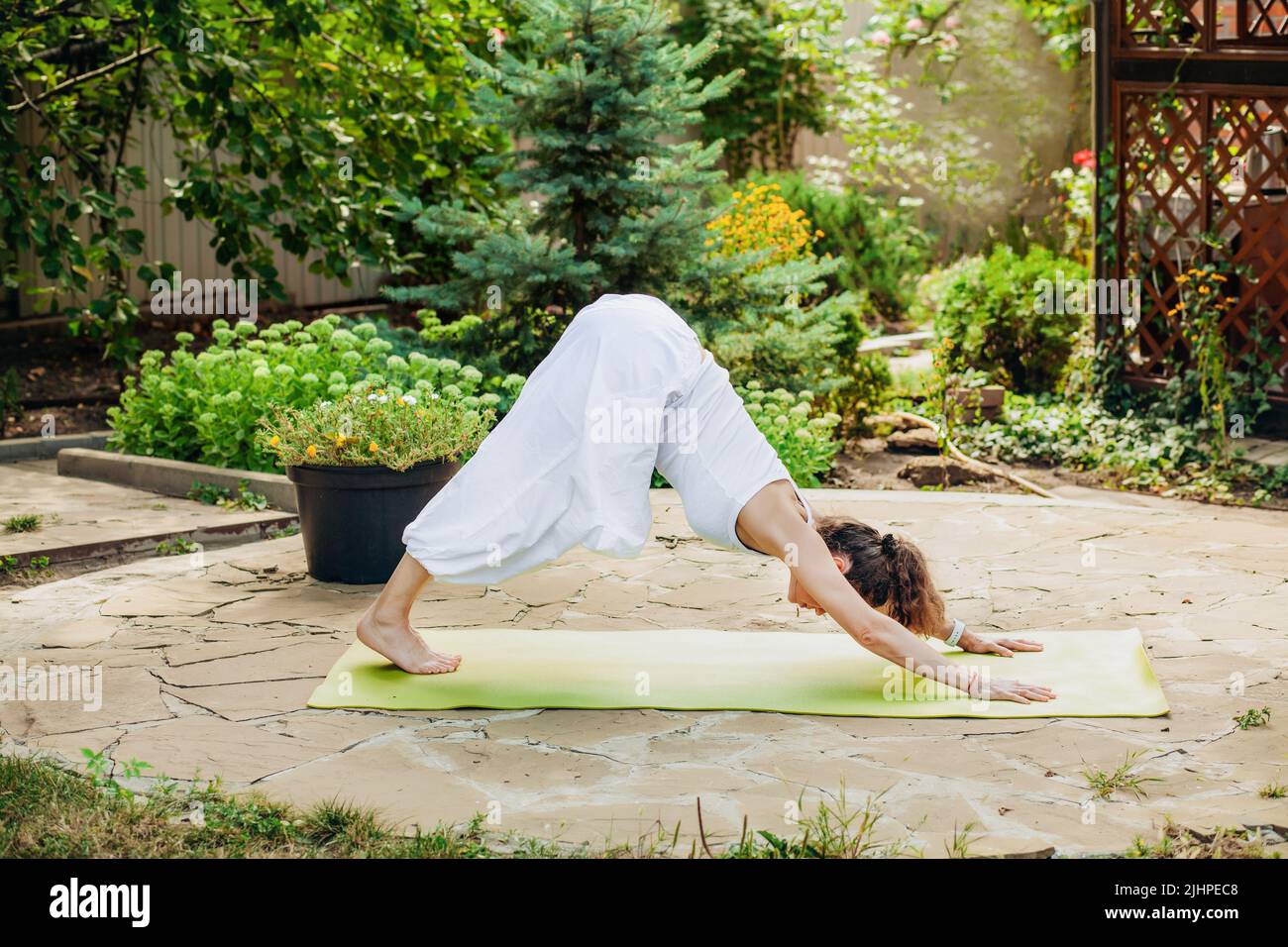 Young woman practices yoga in the garden - Parvatasana, Mountain Pose ...
