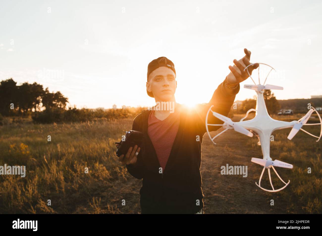 Young man showing drone to camera, sunset flare Stock Photo - Alamy