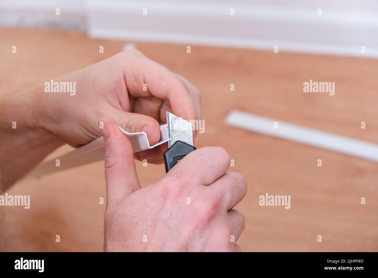 A man cuts the floor skirting boards to a suitable size for ...
