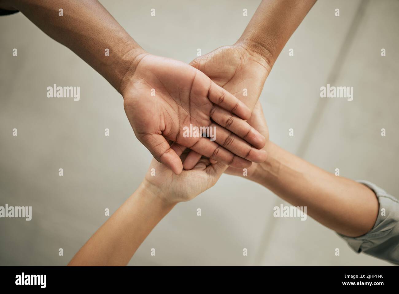 Close up of four colleagues putting hands together in the office ...