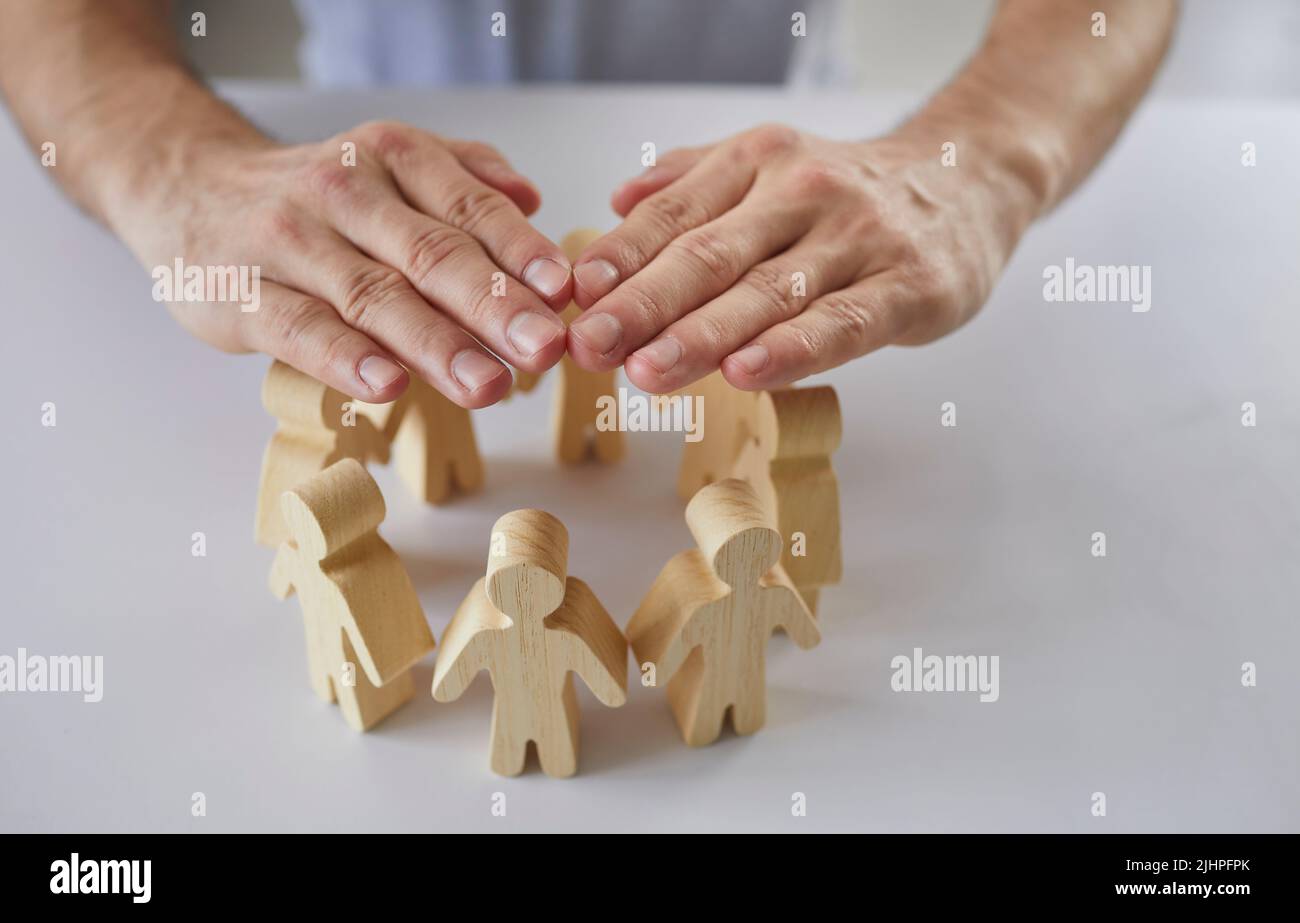 Man covering wooden human figures like corporate manager protecting ...