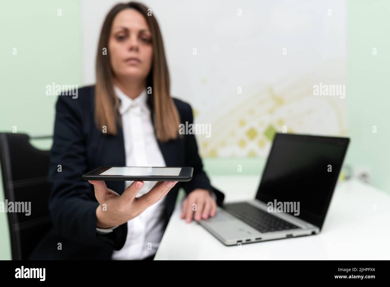 Businesswoman Holding Tablet With One Hand And Having Lap Top On Desk ...